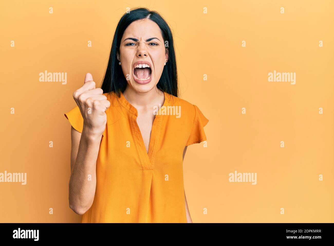 Beautiful young woman wearing casual clothes angry and mad raising fist ...