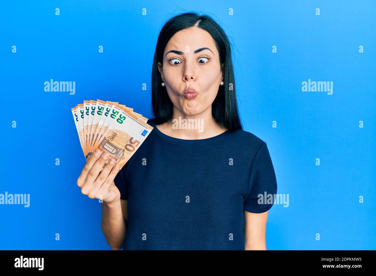 Beautiful young woman holding bunch of 50 euro banknotes making fish ...