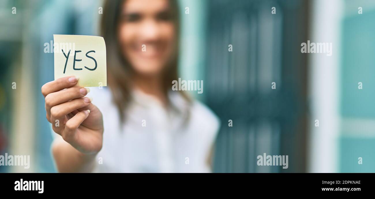 Beautiful latin teenager girl smiling happy holding yes reminder paper ...