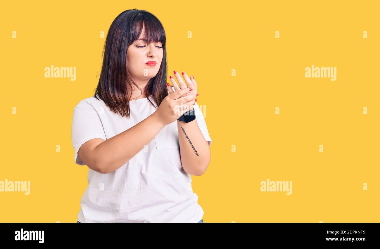 Young plus size woman wearing casual clothes suffering pain on hands ...