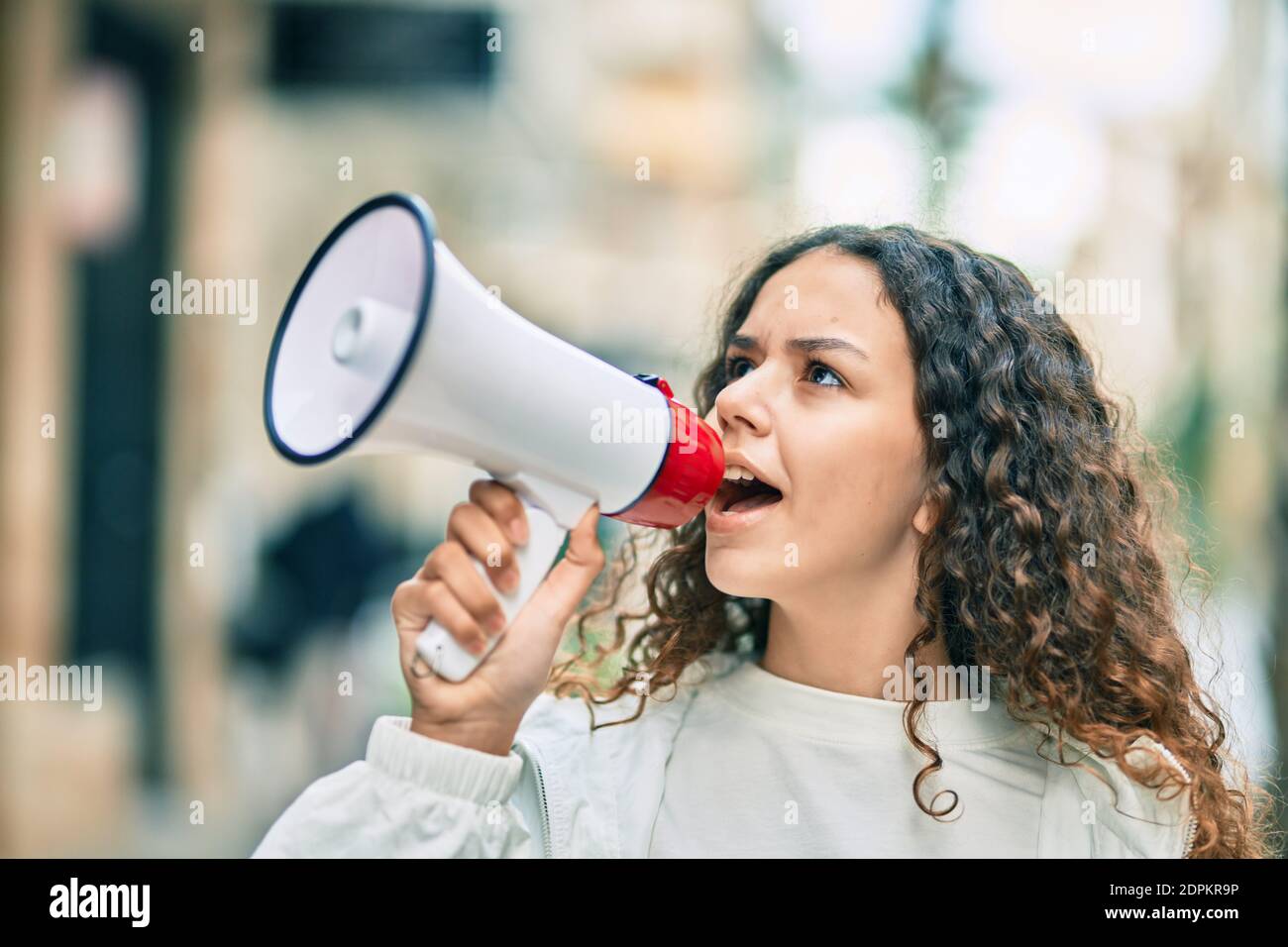 Hispanic child girl shouting angry using megaphone at the city Stock ...