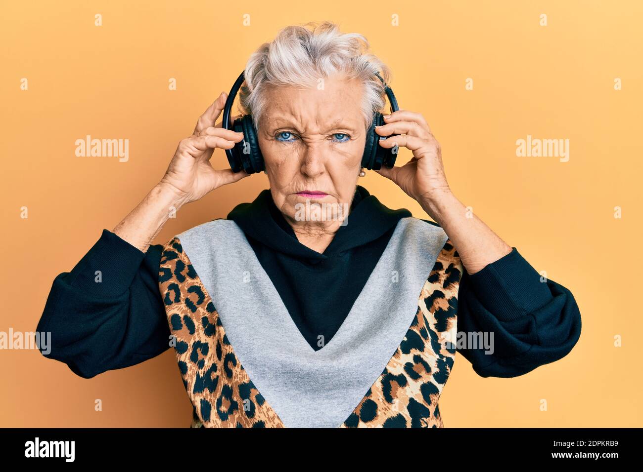 Senior grey-haired woman listening to music using headphones depressed ...
