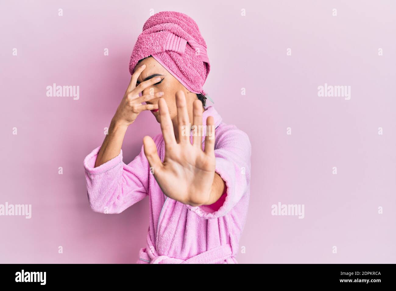 Young man wearing woman make up wearing shower towel on head and ...