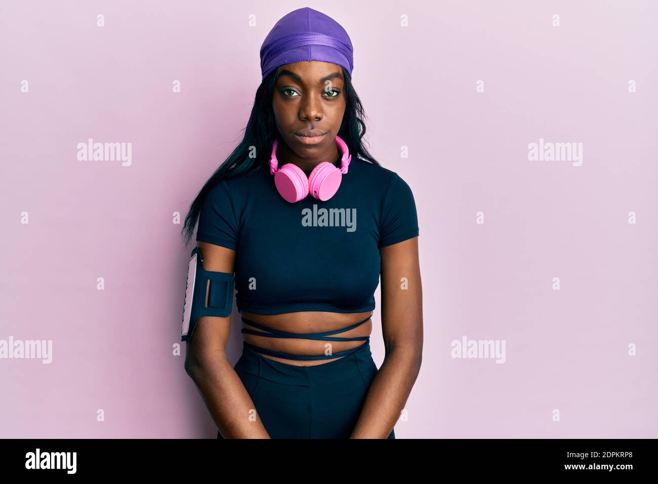 Young african american woman wearing gym clothes and using headphones ...