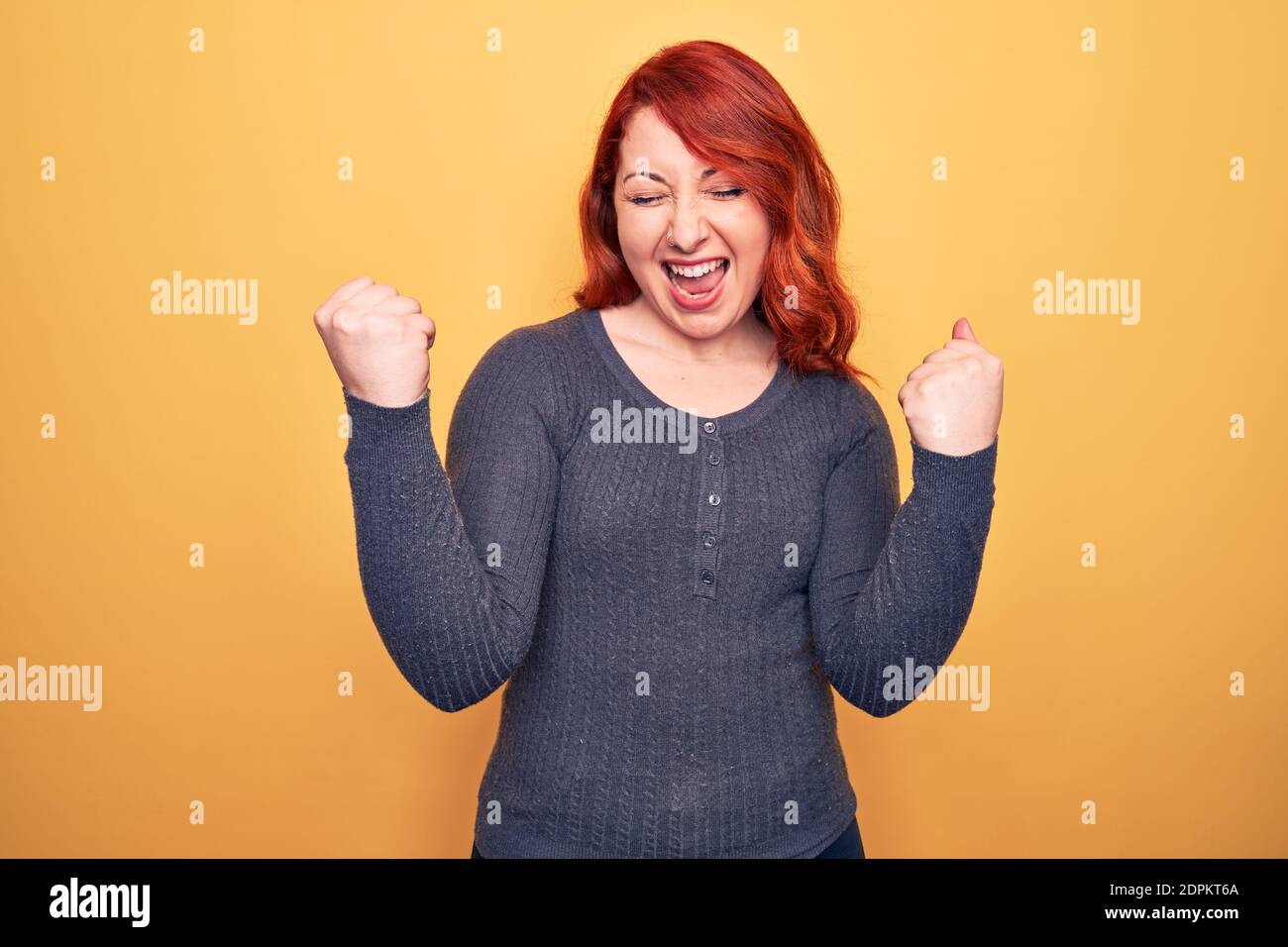 Young beautiful redhead woman wearing casual sweater standing over ...