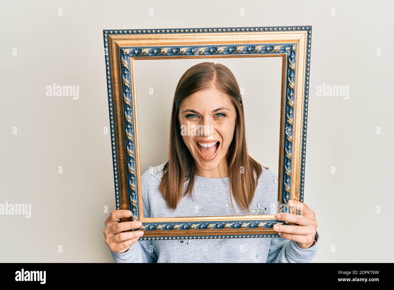 Beautiful caucasian woman holding empty frame smiling and laughing hard ...