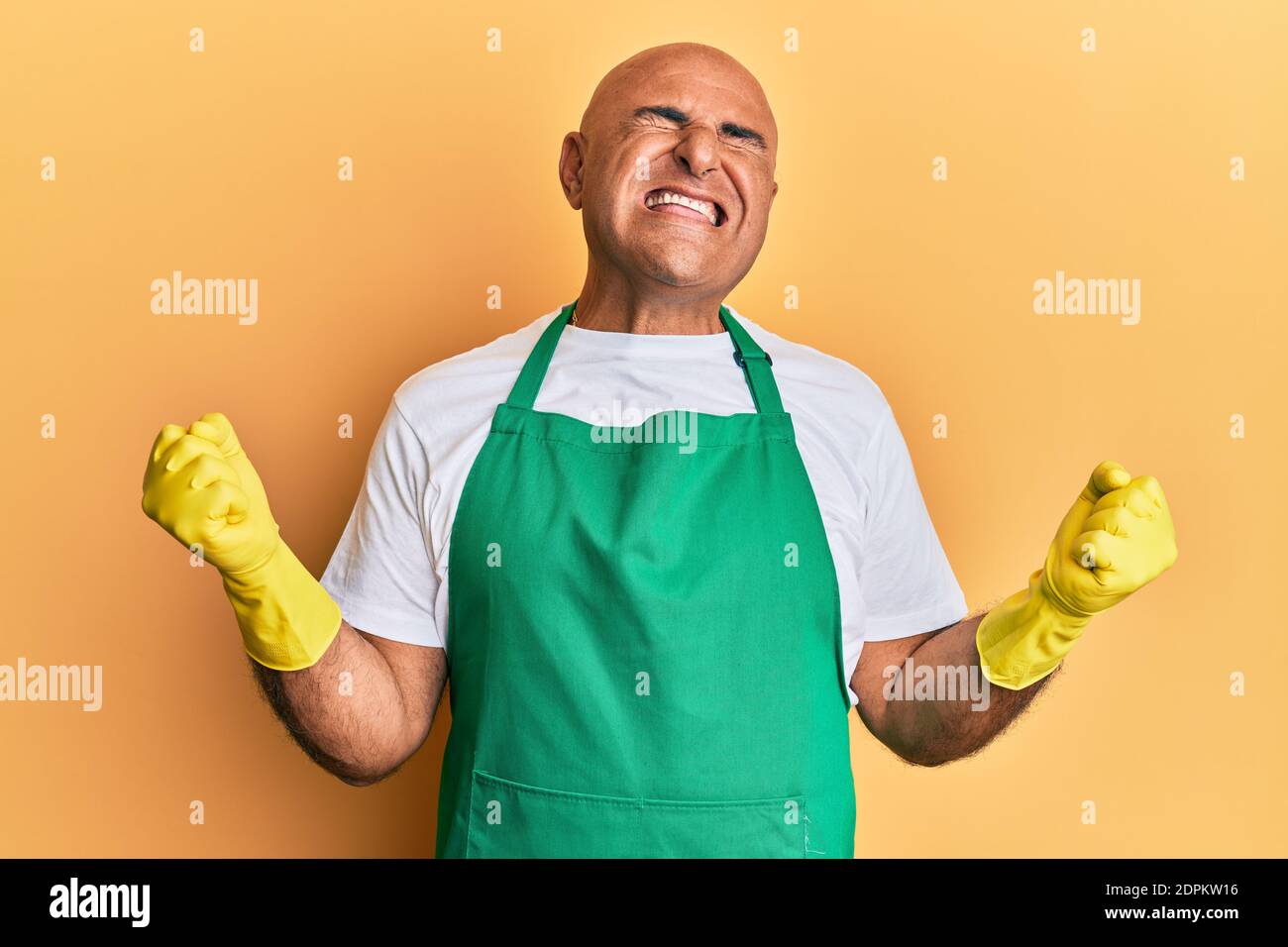 Mature middle east man wearing cleaner apron and gloves very happy and ...