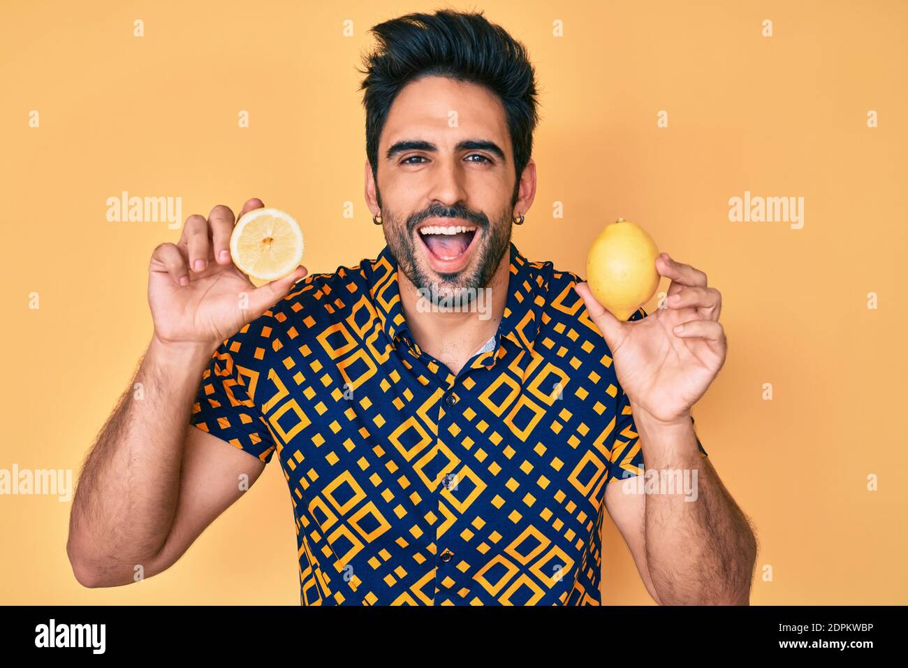Handsome hispanic man with beard holding lemon smiling and laughing ...