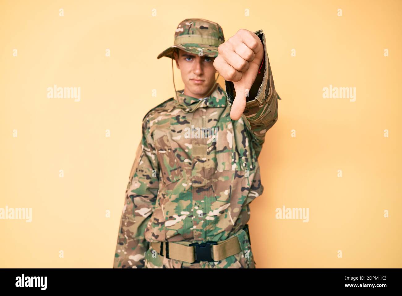 Young handsome man wearing camouflage army uniform looking unhappy and ...