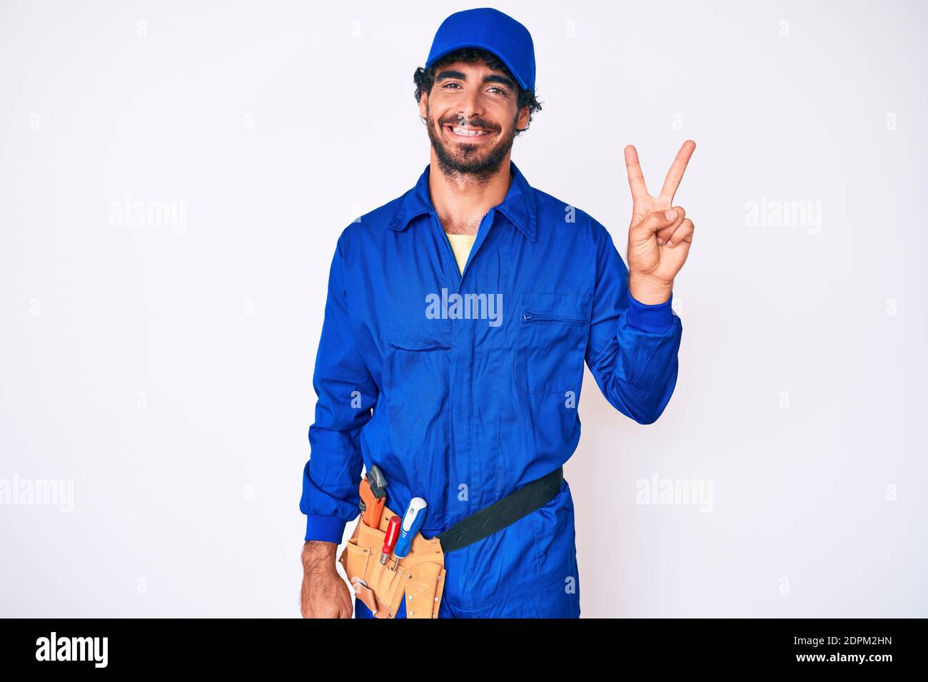 Handsome young man with curly hair and bear weaing handyman uniform ...