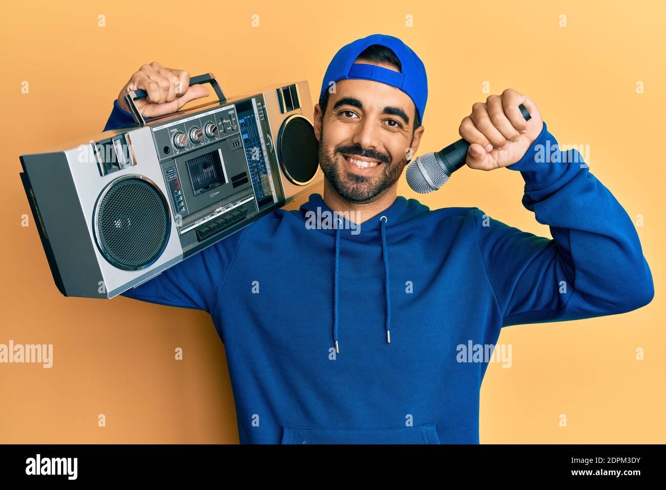 Young hispanic man holding boombox, listening to music singing with ...