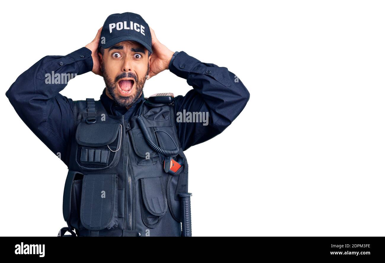 Young hispanic man wearing police uniform crazy and scared with hands ...