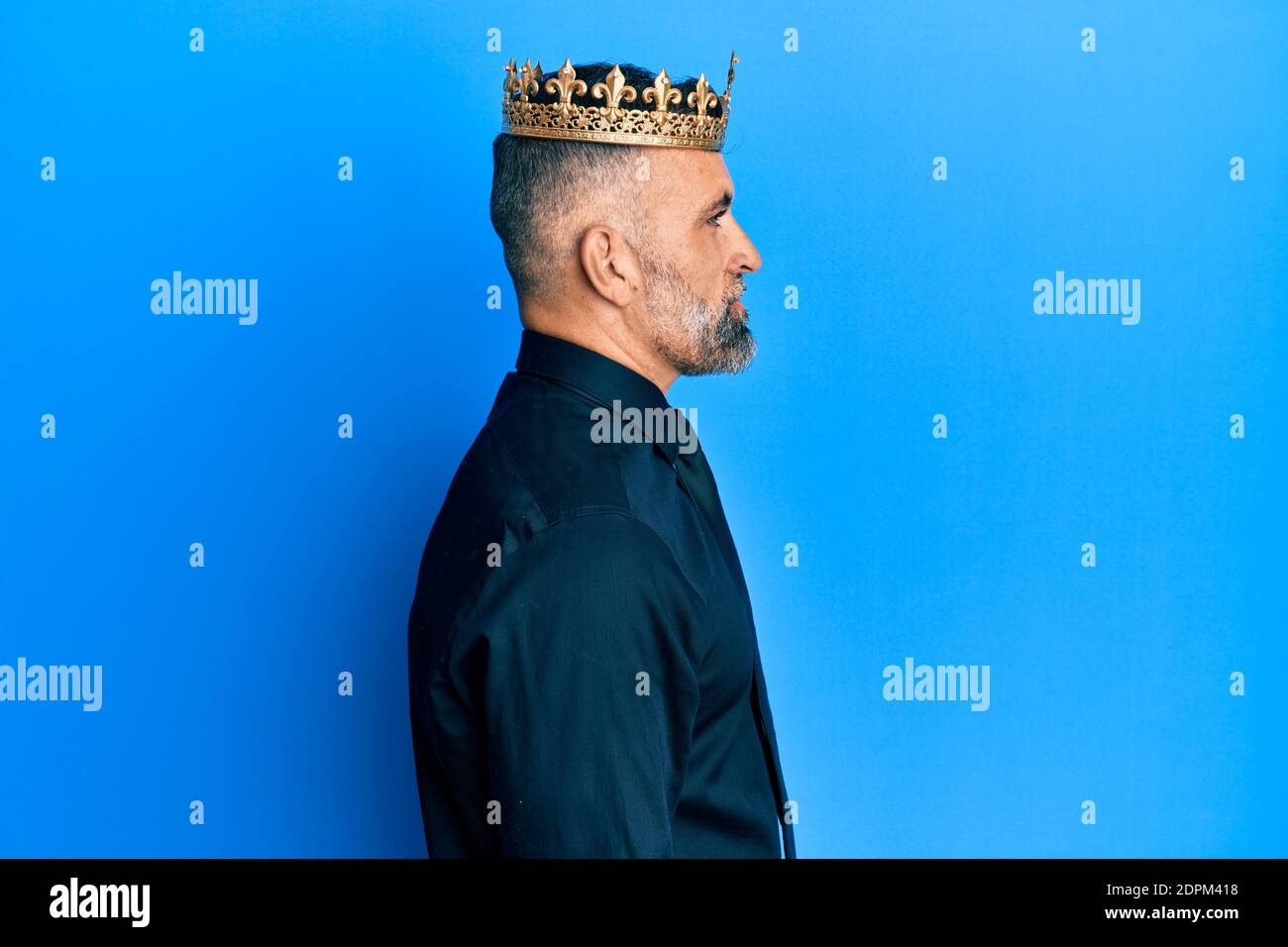 Middle age handsome business man wearing king crown looking to side ...