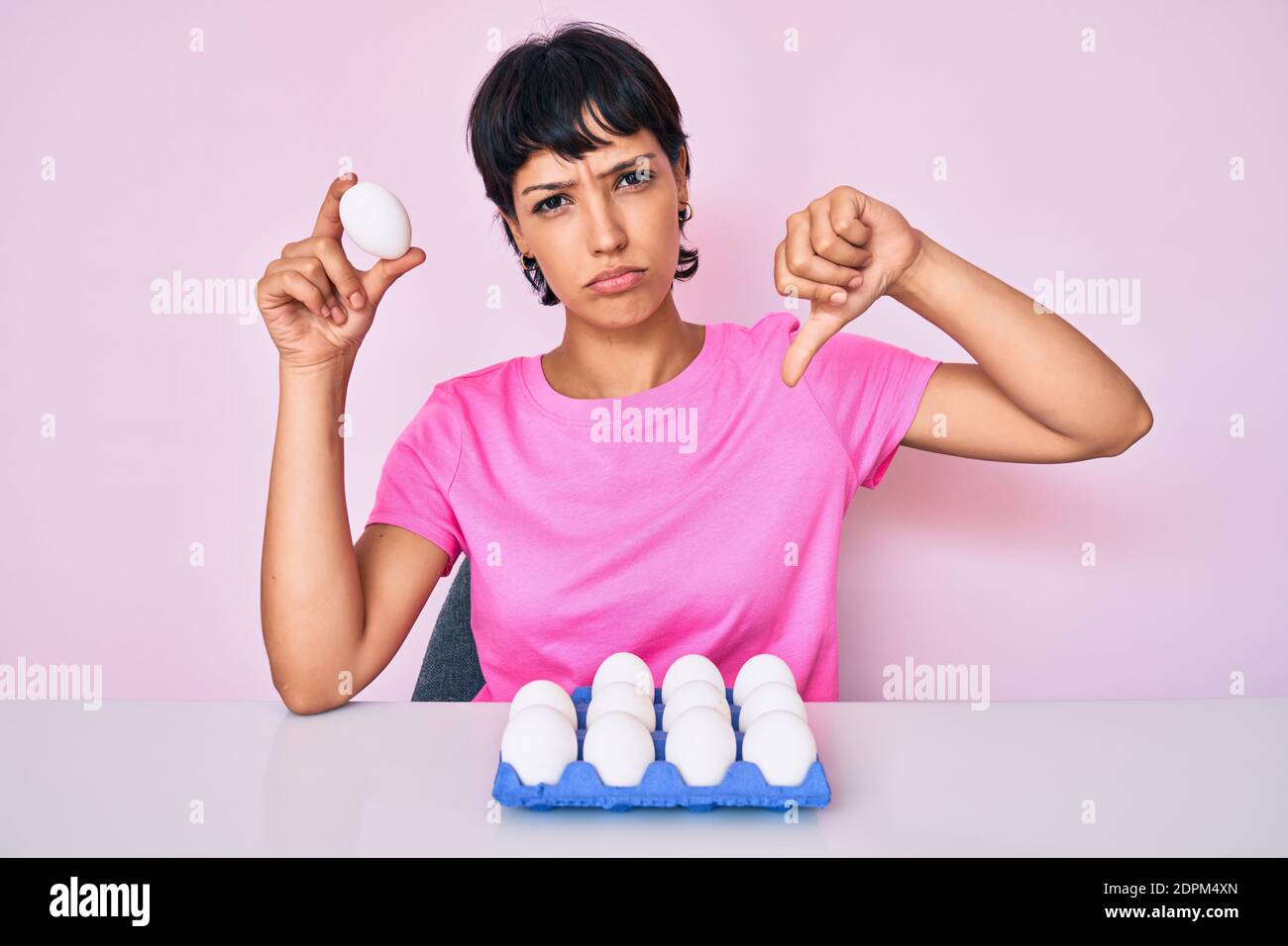 Beautiful brunettte woman showing fresh white eggs with angry face ...