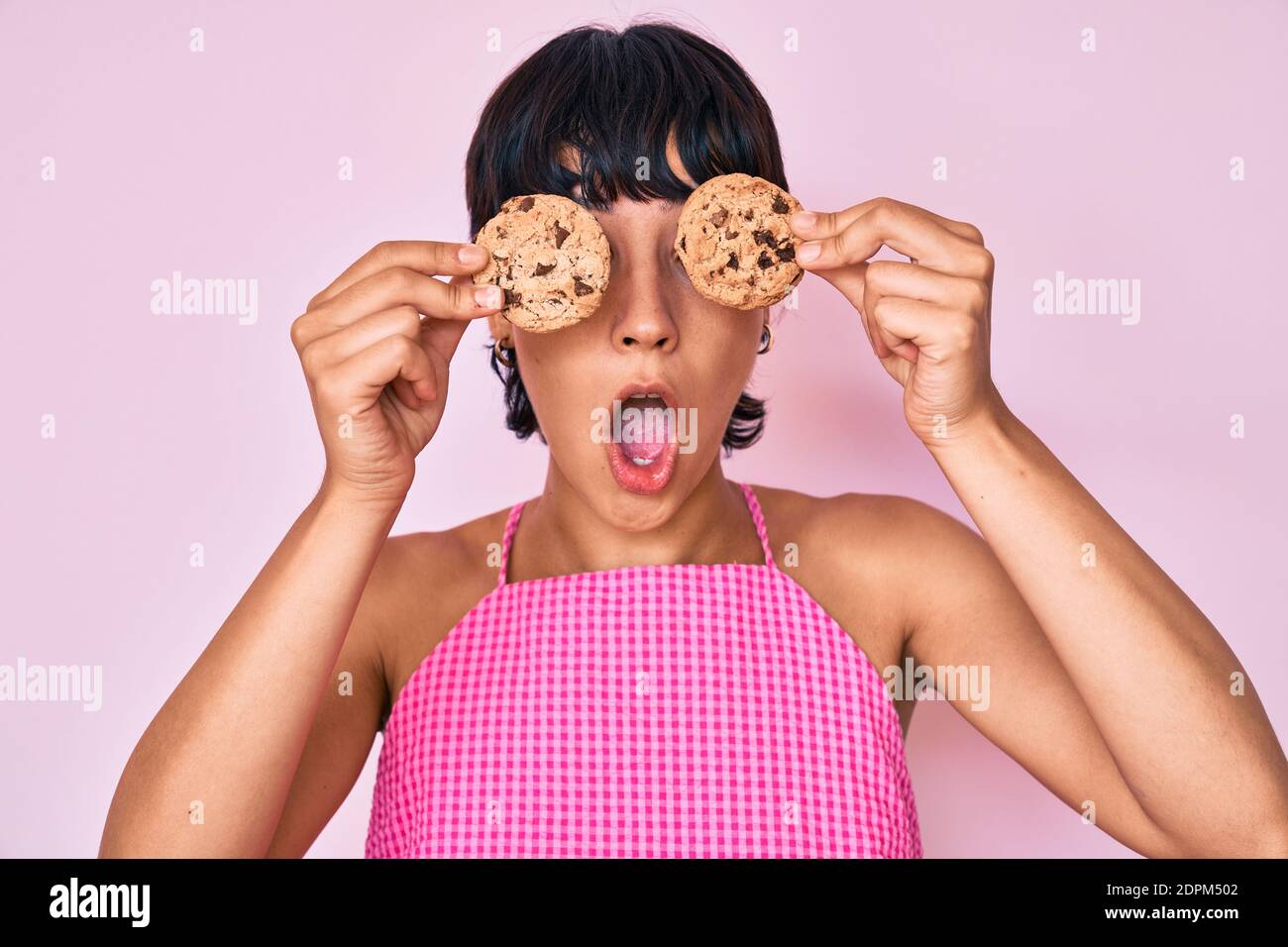 Beautiful brunettte woman holding chocolate chips cookies on eyes ...