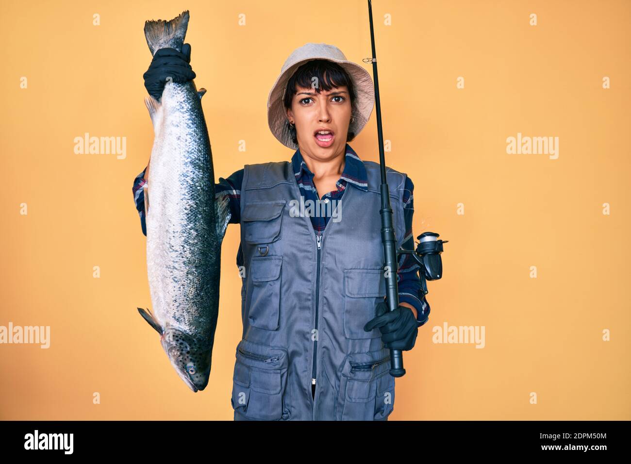 Beautiful brunettte fisher woman holding fishing rod and raw salmon ...