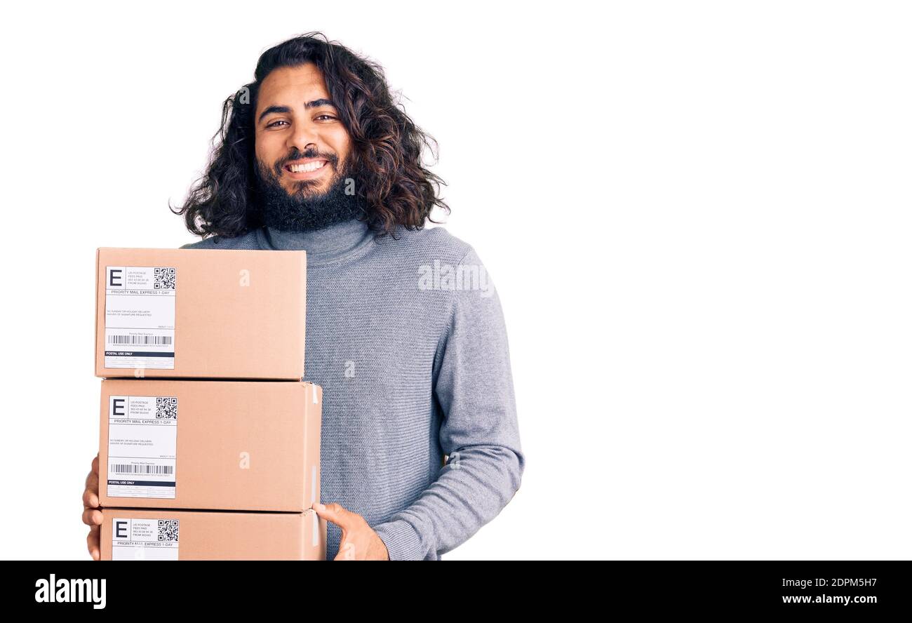 Young arab man holding delivery package looking positive and happy ...