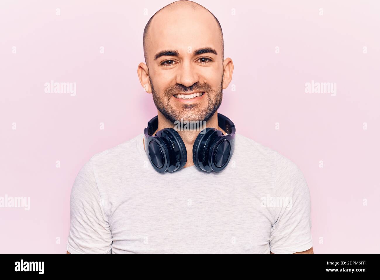 Young handsome bald man listening to music using headphones with a ...