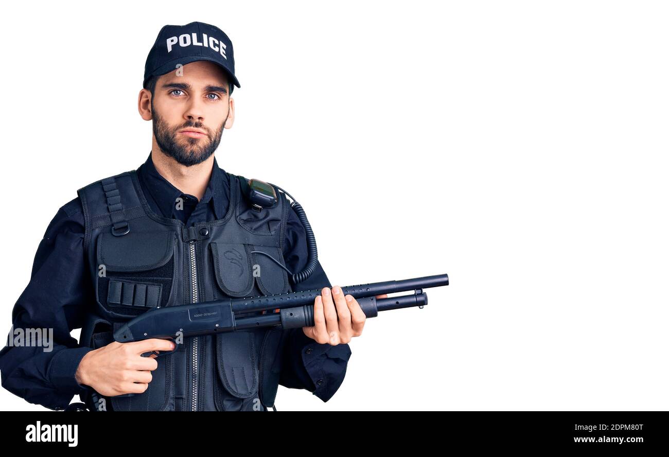 Young handsome man with beard wearing police uniform holding shotgun ...