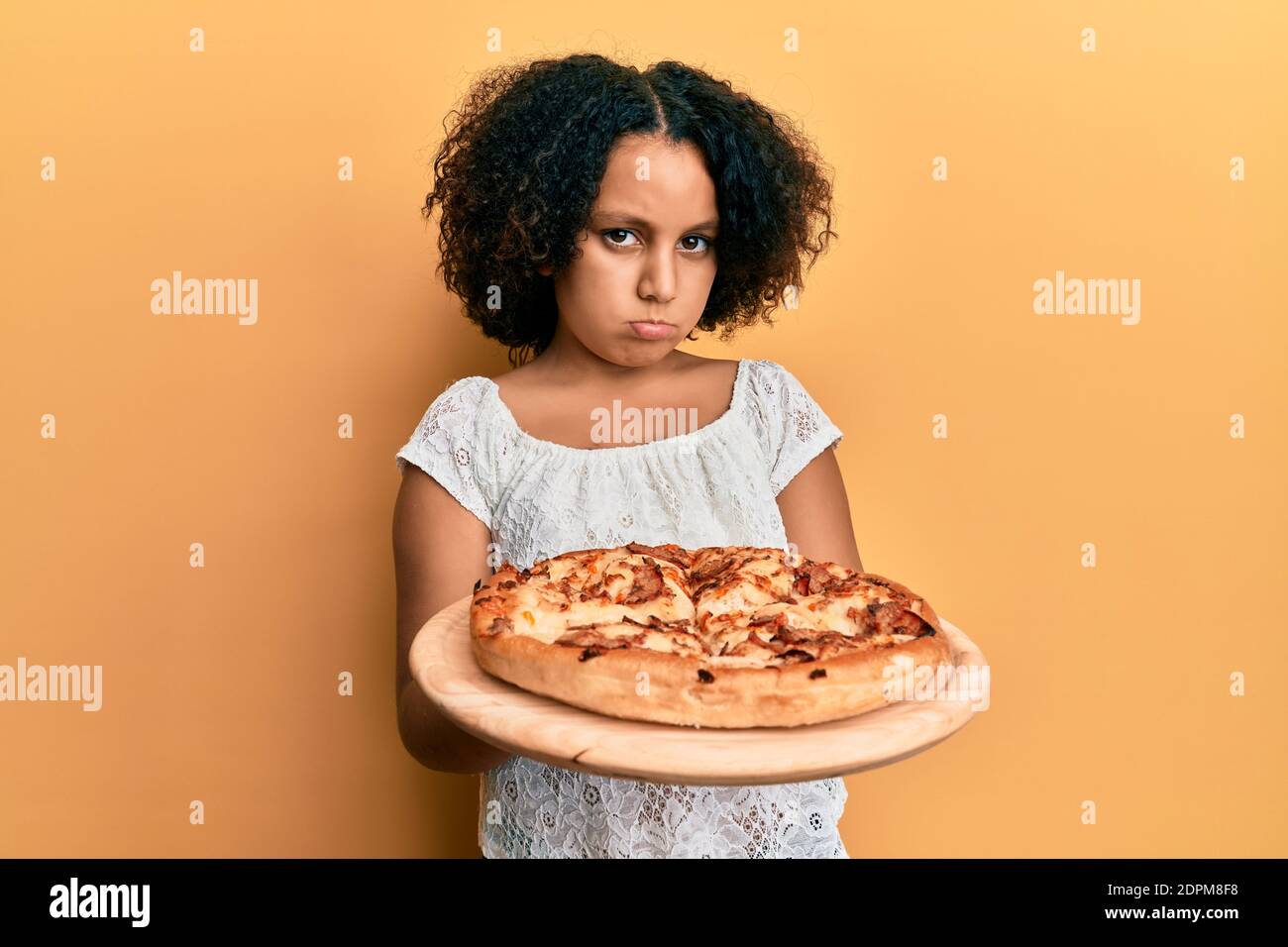 Young little girl with afro hair holding italian pizza depressed and ...