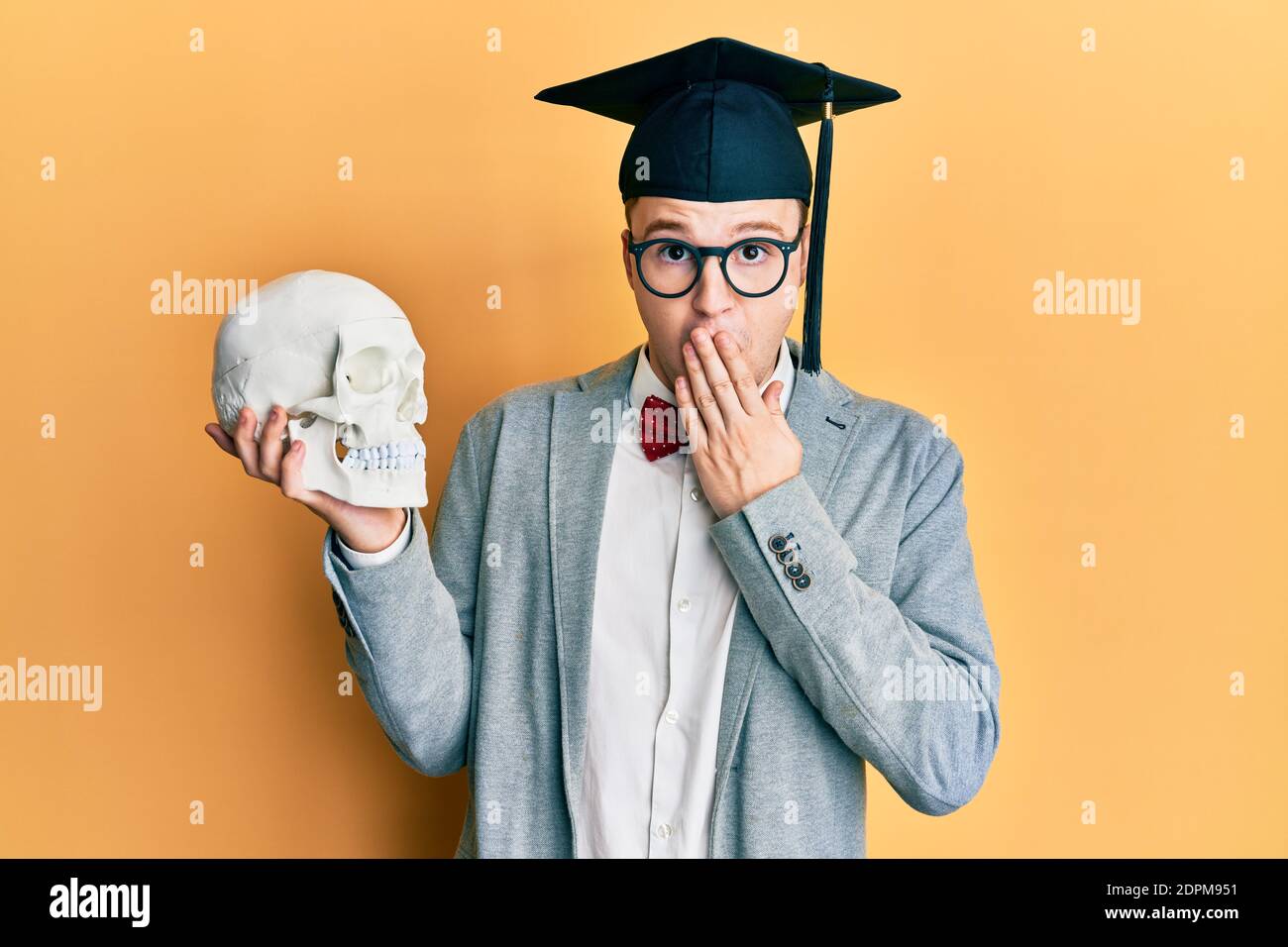 Young caucasian nerd man wearing glasses and graduation cap holding ...