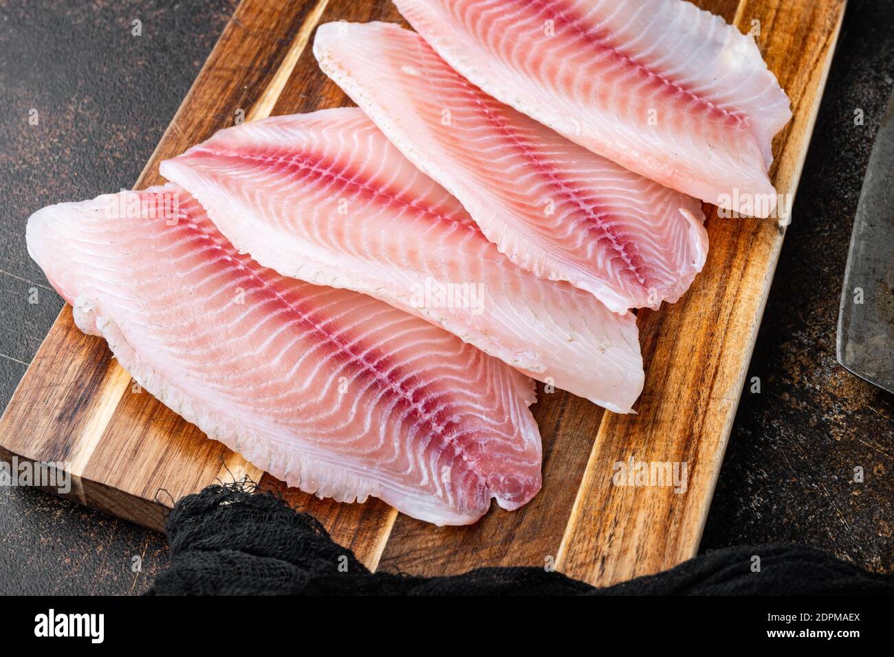 Tilapia fish fillet meat cuts, on old rustic background Stock Photo - Alamy