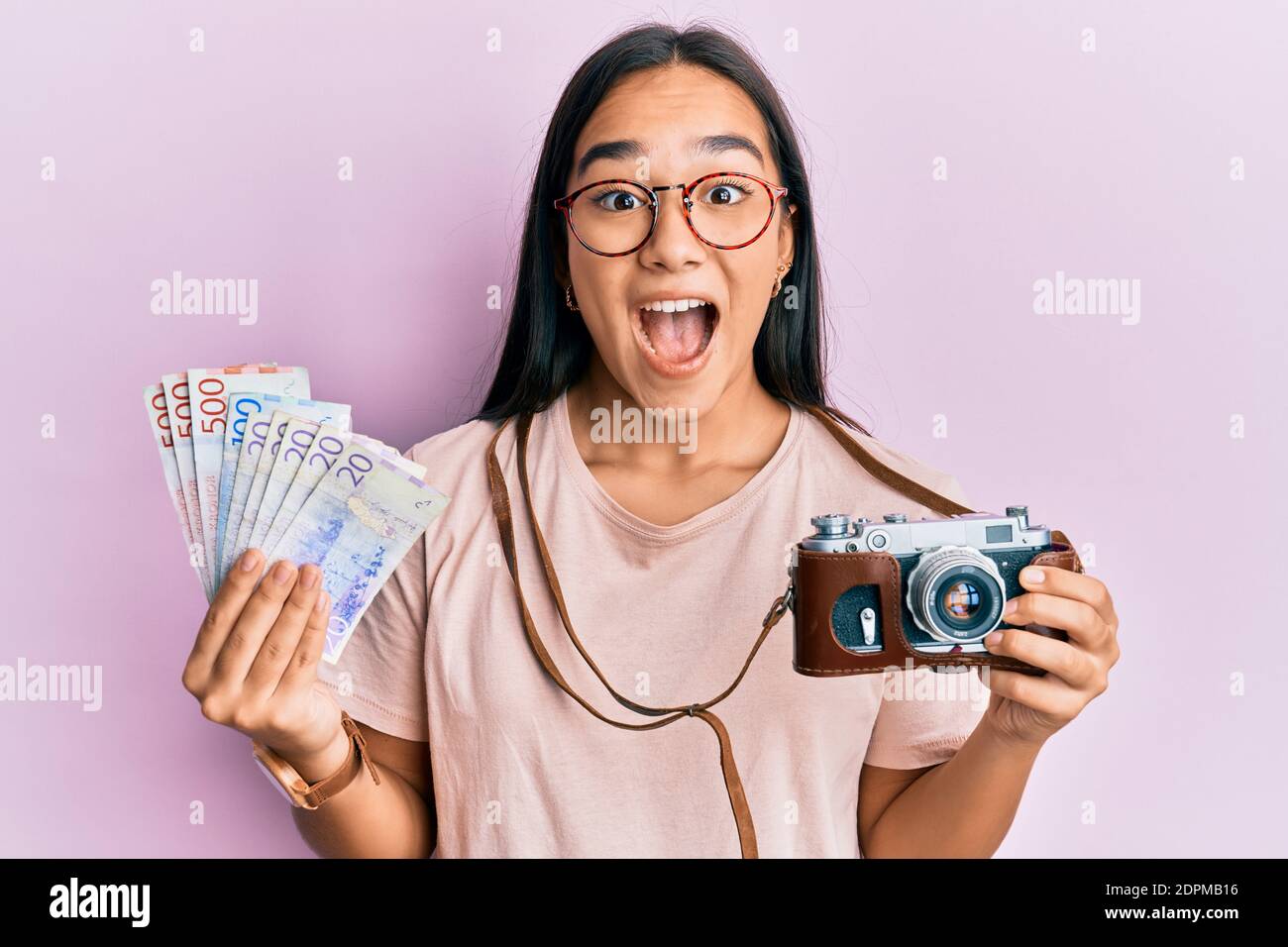 Young asian woman holding vintage camera and swedish krona celebrating ...