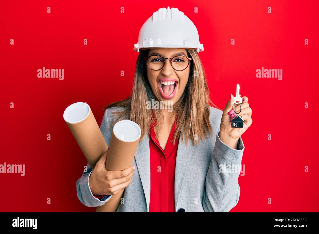 Beautiful brunette woman wearing safety helmet holding blueprints smiling and laughing hard out ...