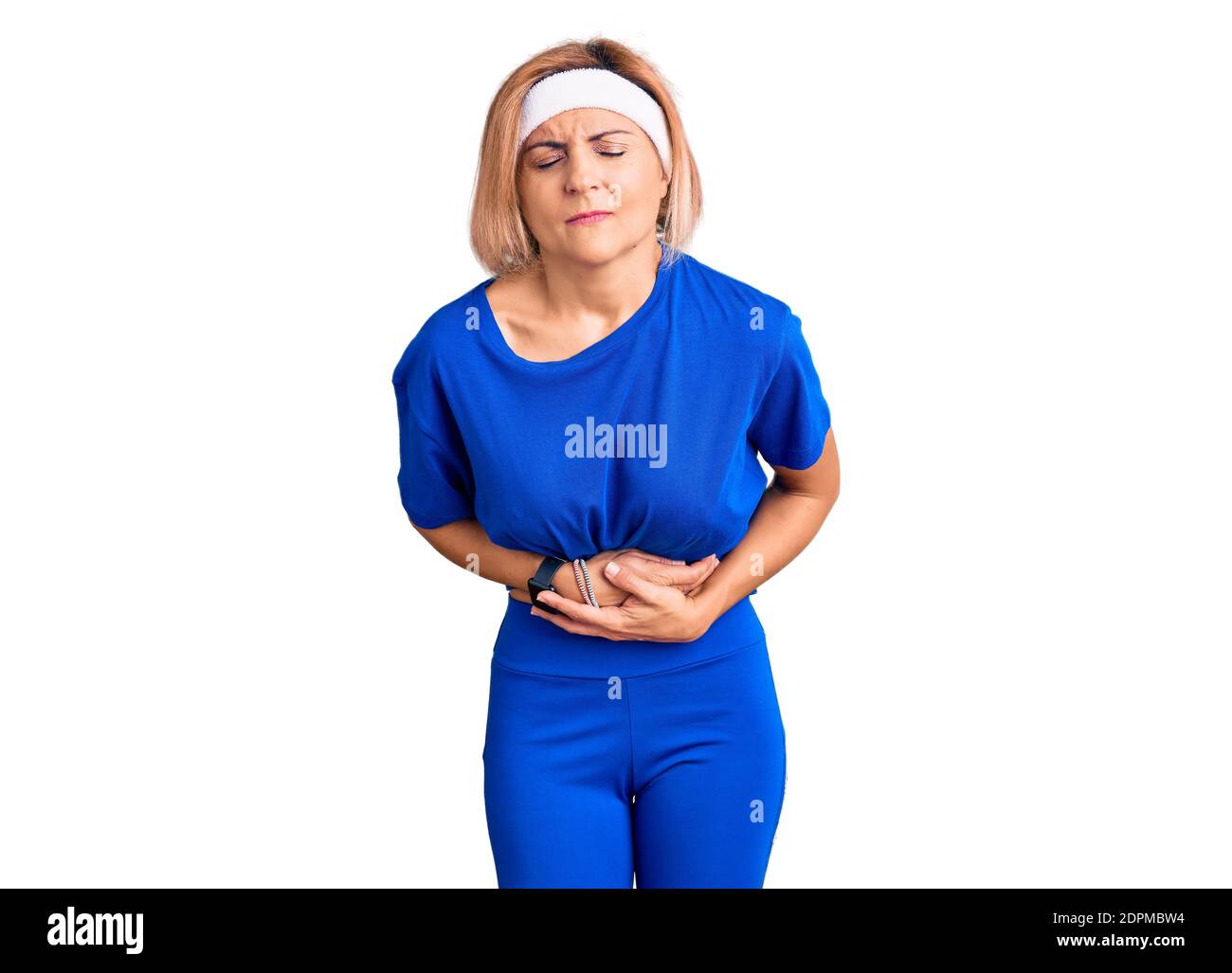 Young blonde woman wearing sportswear with hand on stomach because ...