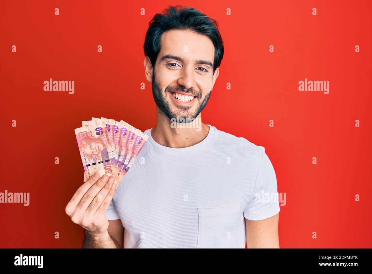 Young hispanic man holding south african rand banknotes looking ...