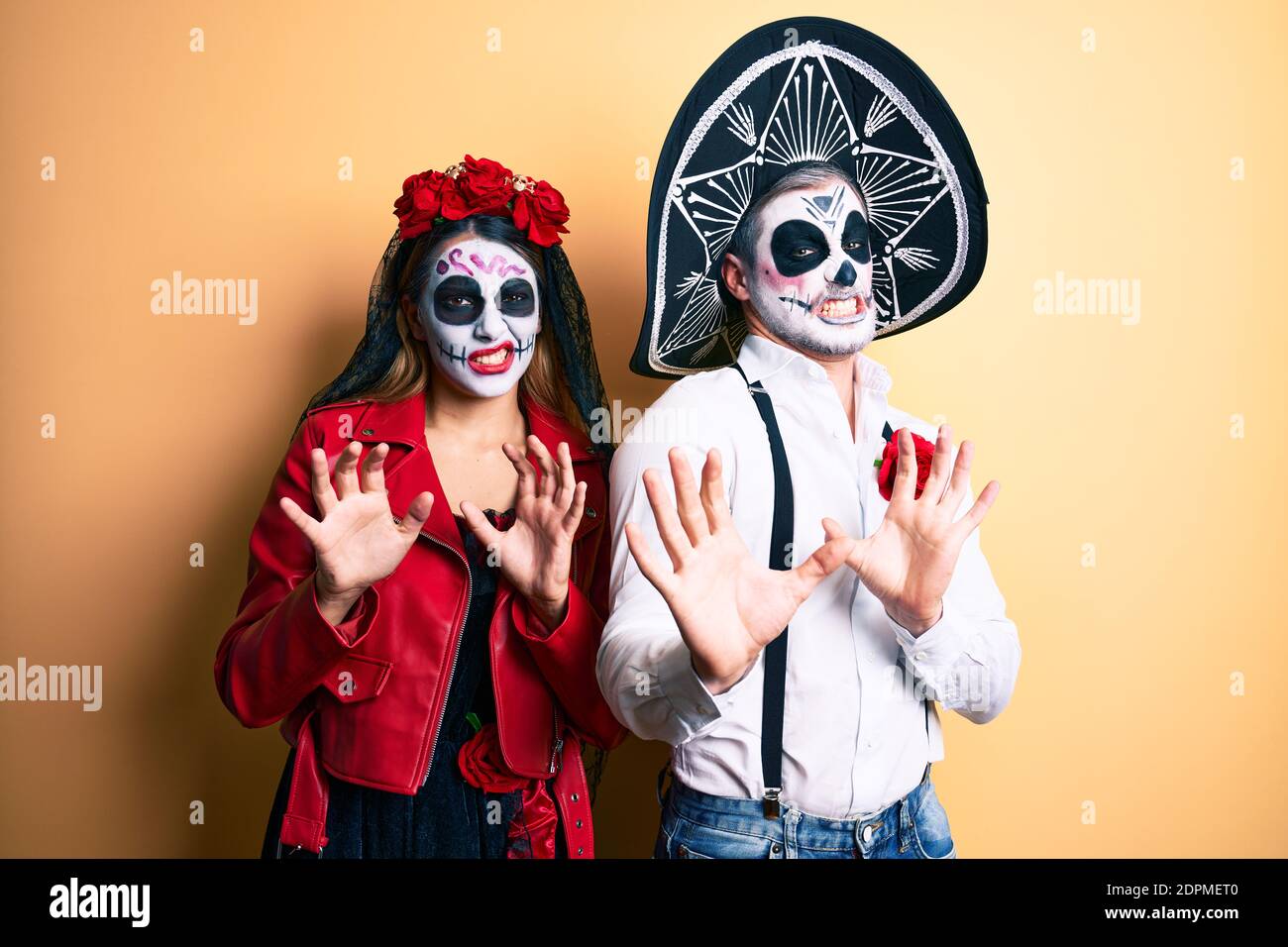 Couple wearing day of the dead costume over yellow disgusted expression ...