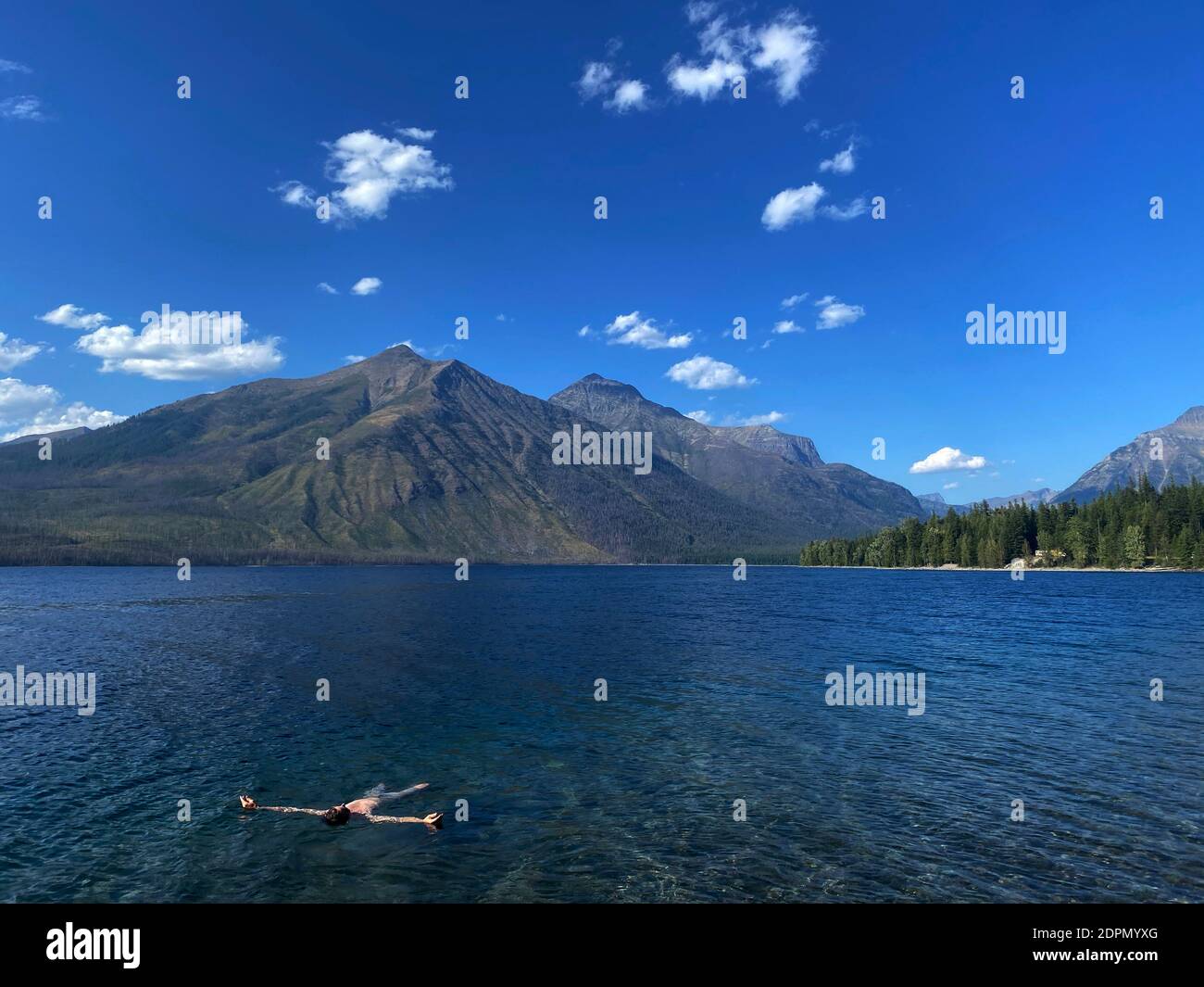 A man floats on his back in McDonald Lake in Glacier National Park, MT ...