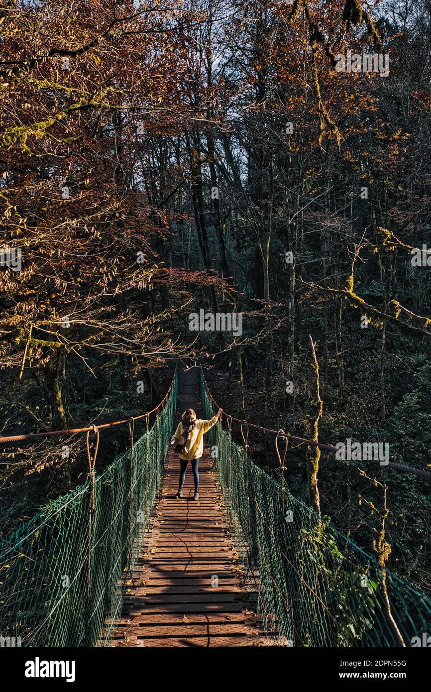 Young woman crossing suspension bridge Stock Photo - Alamy