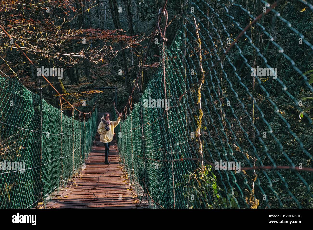 Young woman crossing suspension bridge Stock Photo - Alamy