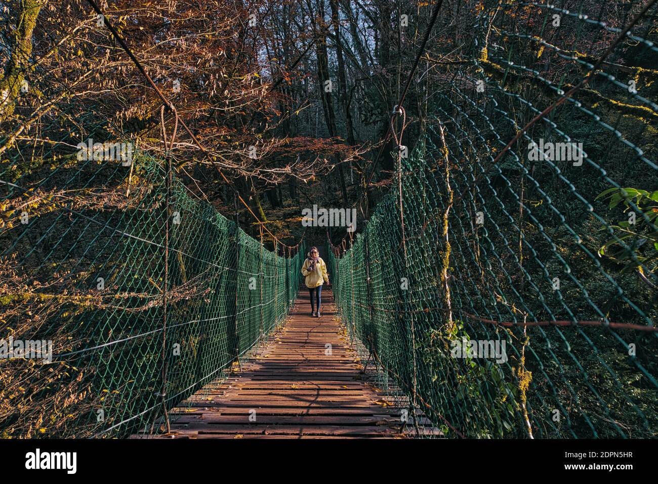 Young woman crossing suspension bridge Stock Photo - Alamy