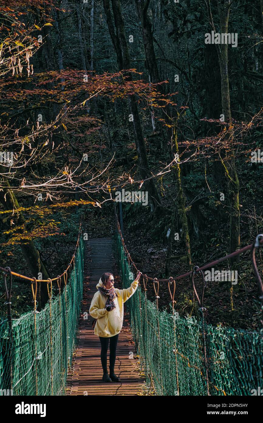 Young woman crossing suspension bridge Stock Photo - Alamy