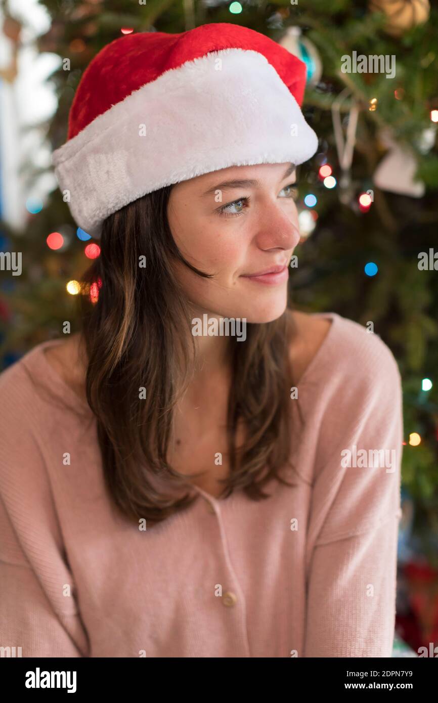 Closeup Pretty Female College Student in Santa hat by christmas Tree ...