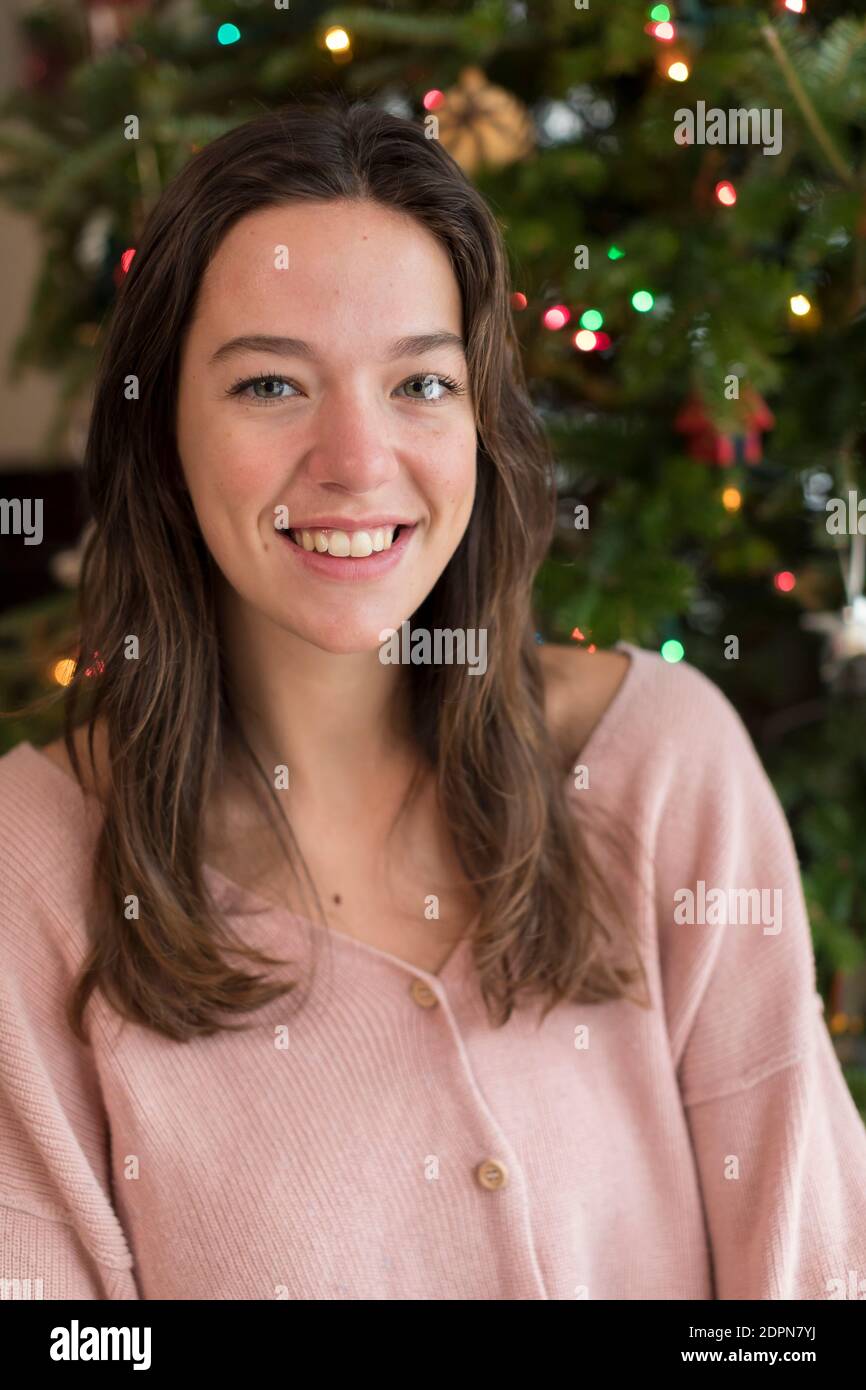Close up of Pretty College-aged woman in front of christmas Tree Stock ...