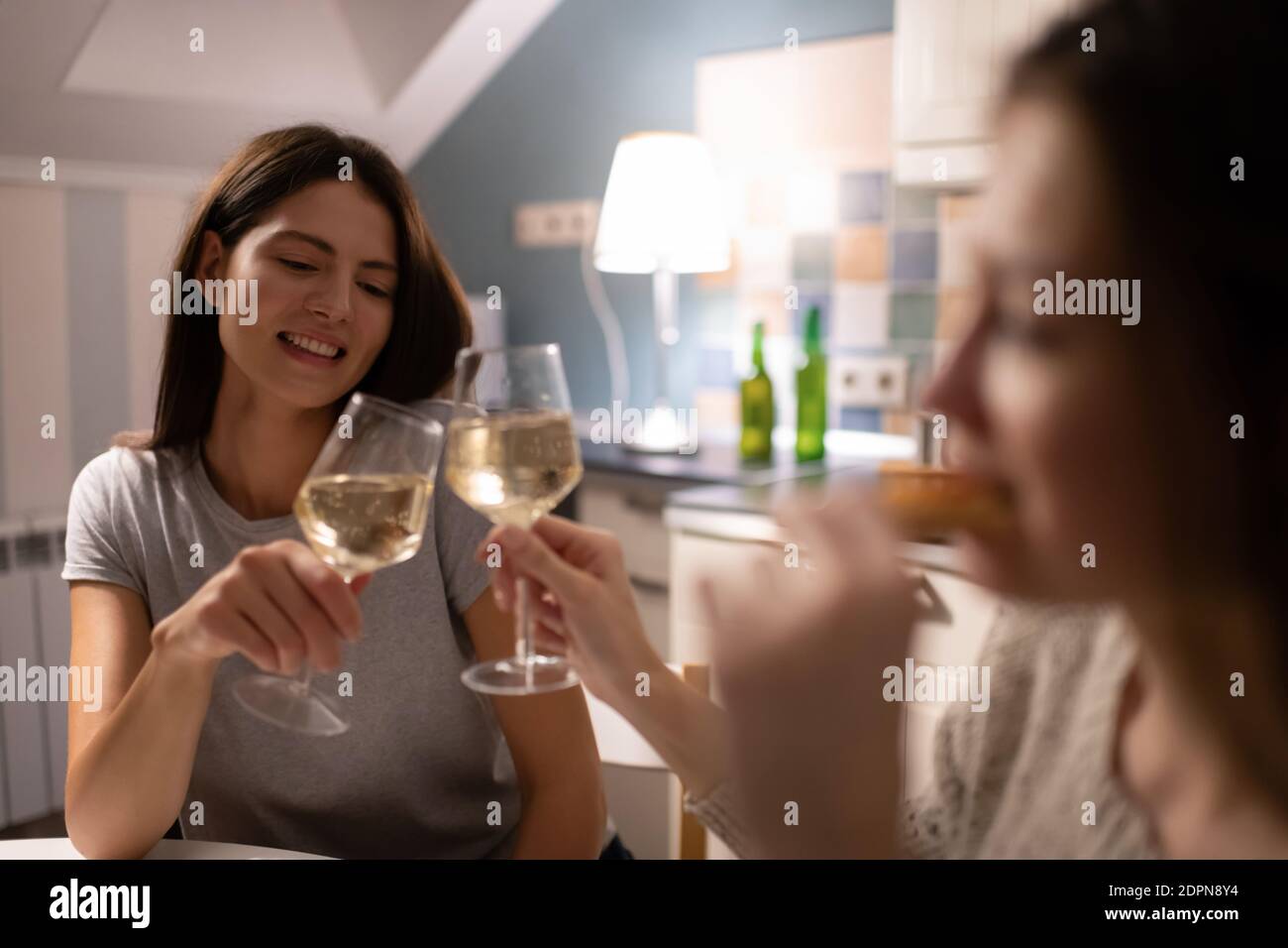 Optimistic young lady smiling and proposing toast to blurred friend ...