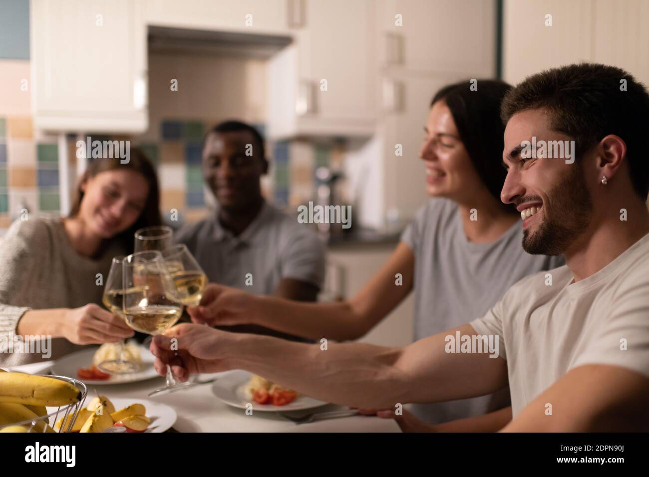 Side view of optimistic guy smiling and proposing toast to multiethnic ...