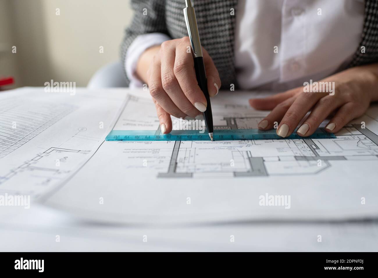 Anonymous designer using pen and ruler to draw line on construction ...