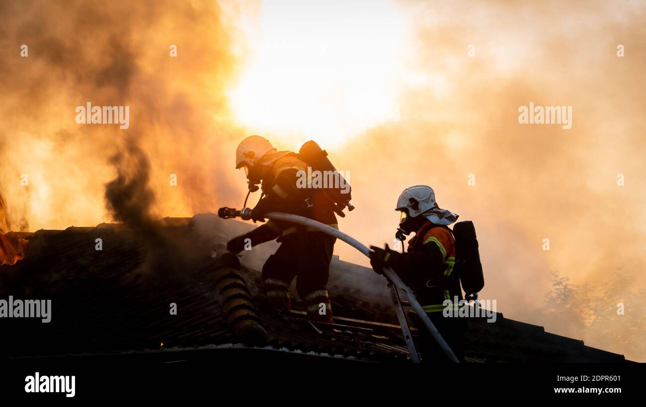 Low Angle View Of Firefighters With Fire Hose Against Smoke Stock Photo ...