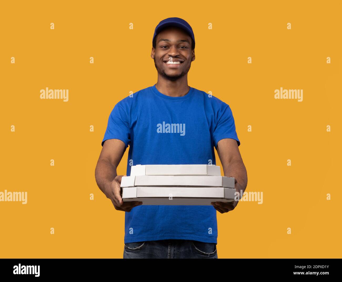 Black delivery man holding pizza boxes, giving it to camera Stock Photo ...