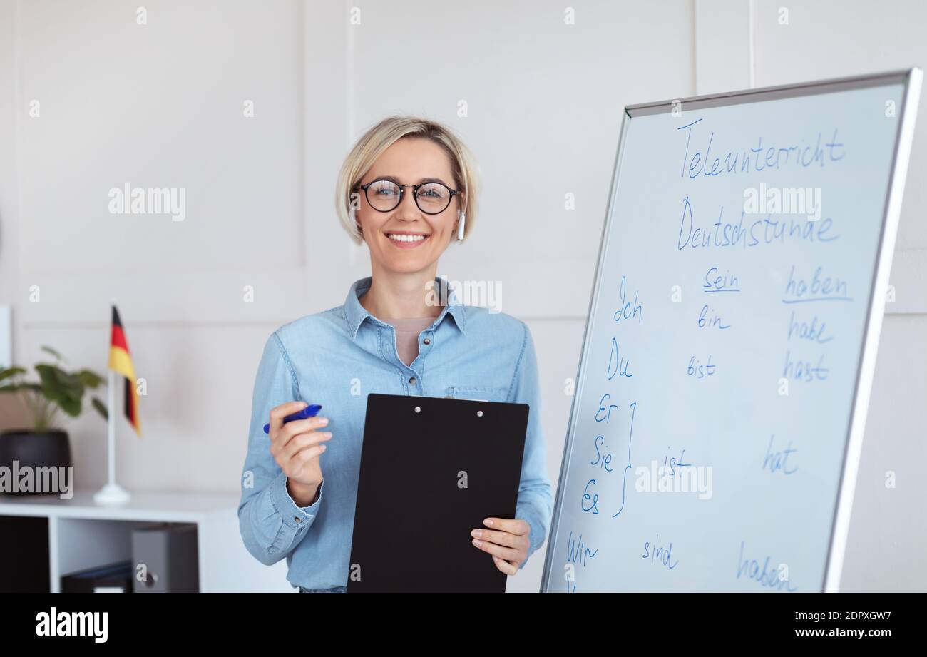 Online schooling. Positive German teacher posing near blackboard with ...