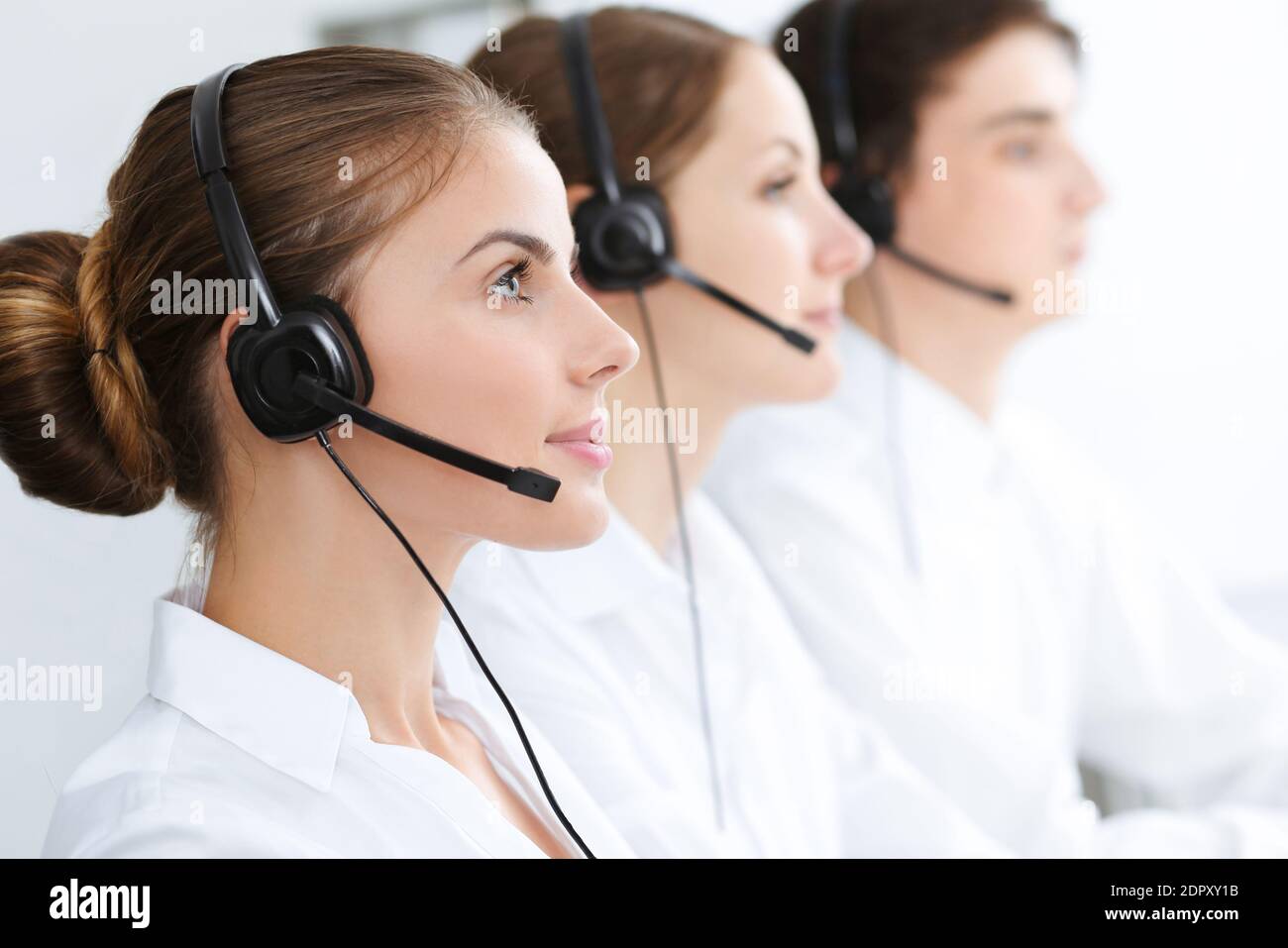 Call center. Beautiful young woman using headset and computer to help ...