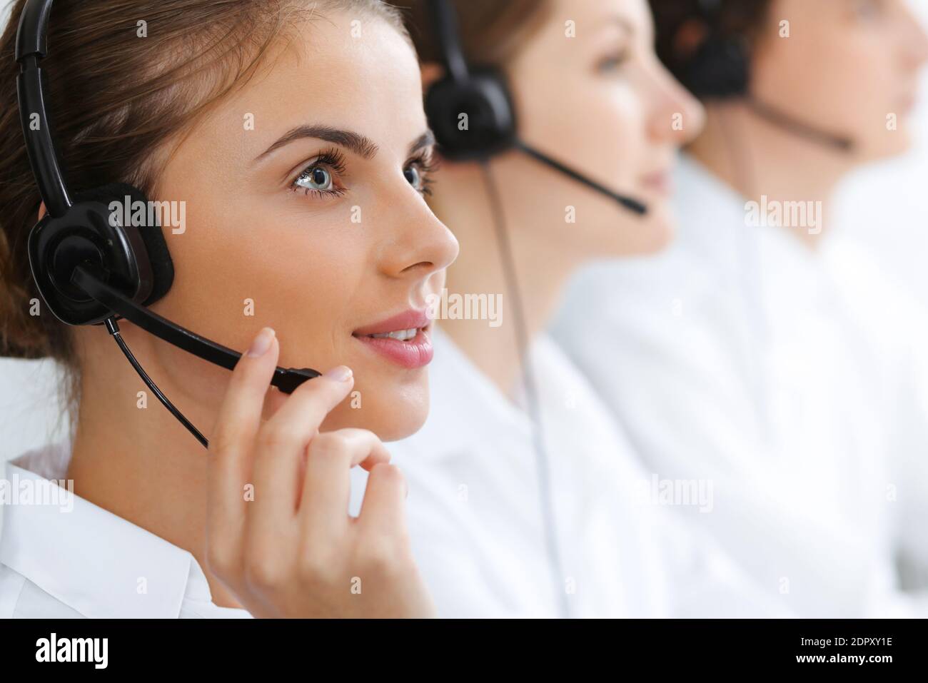 Call center. Beautiful young woman using headset and computer to help ...