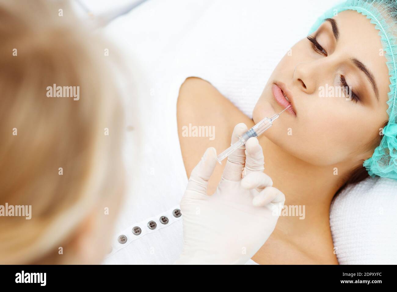Professional cosmetologist making injection in face, lips. Young woman ...