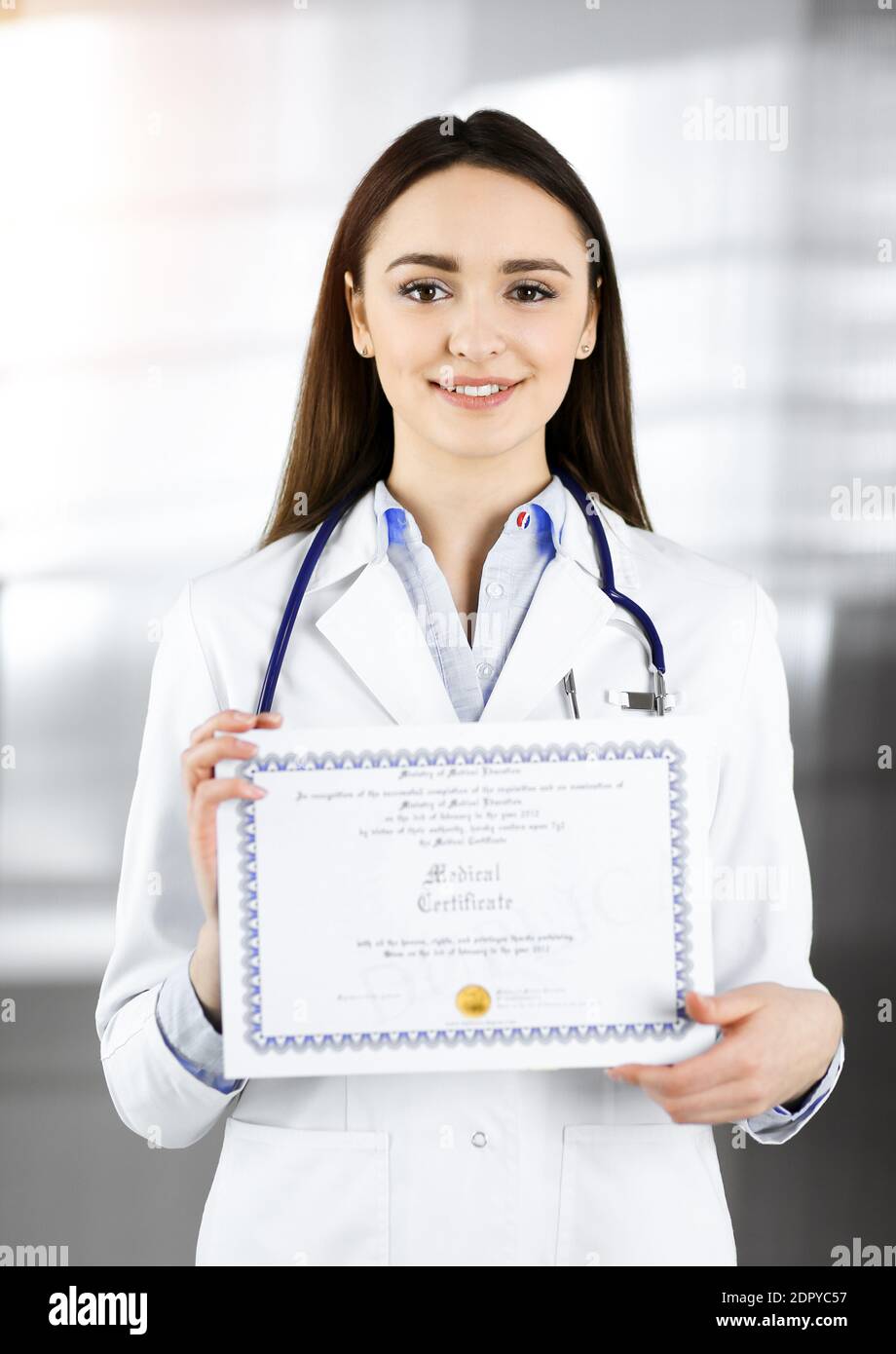 Happy young woman-doctor is holding a certificate in her hands ...