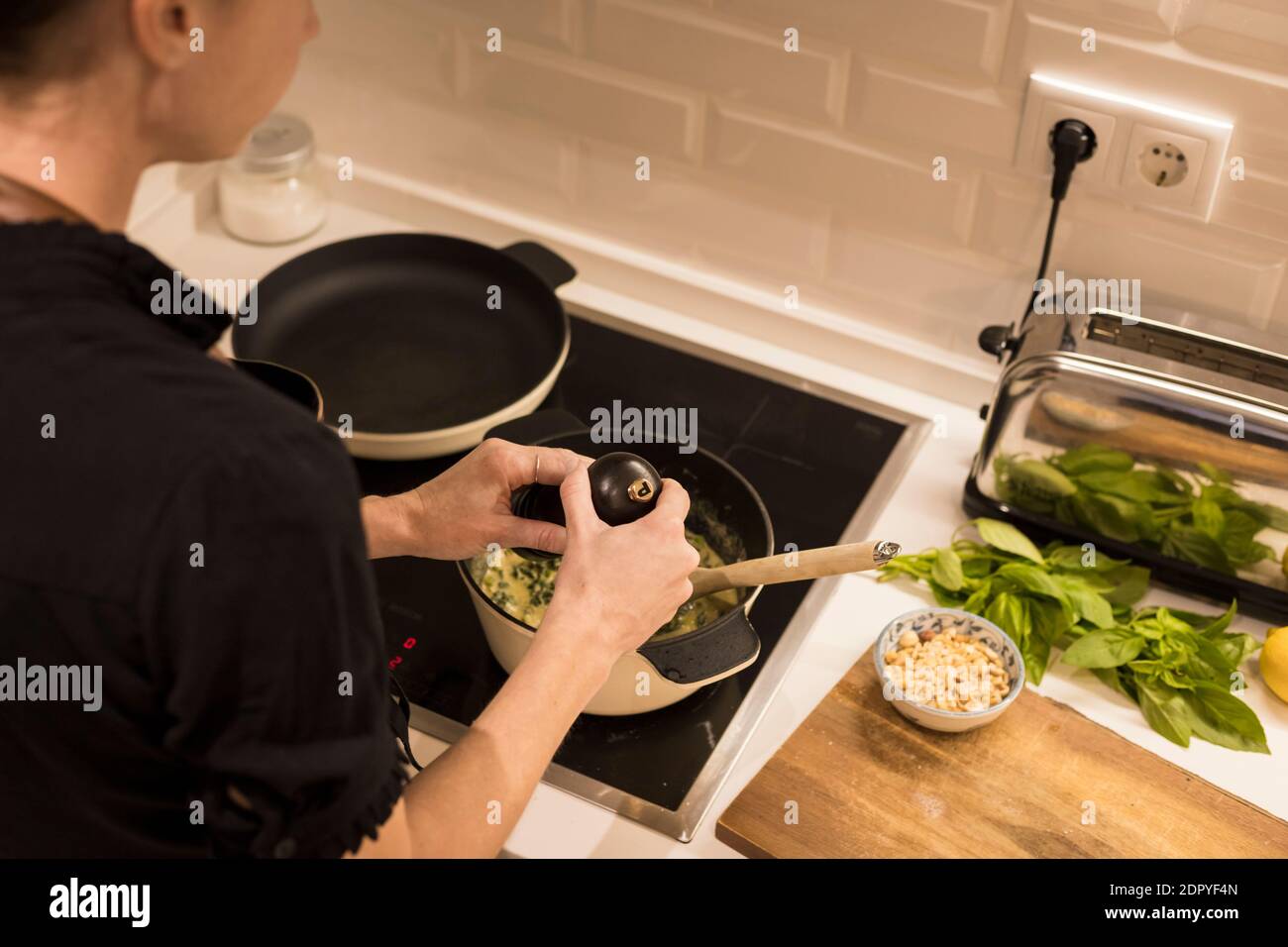 Rear view of a young beautiful girl cooking and preparing vegetarian ...