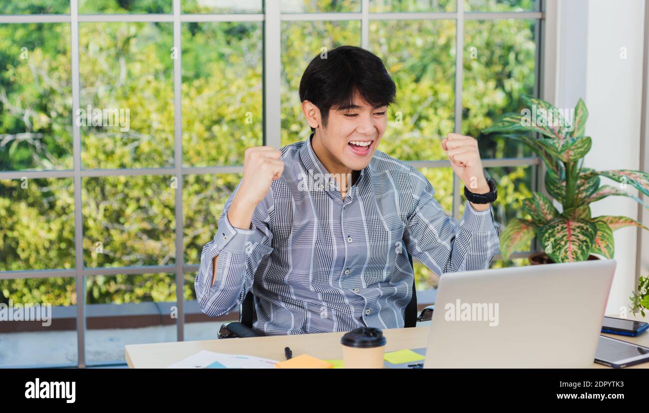 Yes! Happy excited Asian man raising his arm up to celebrate ...